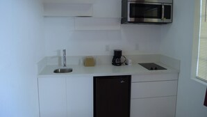 Uma cozinha compacta com micro-ondas embutido, cafeteira e máquina de lavar louça.