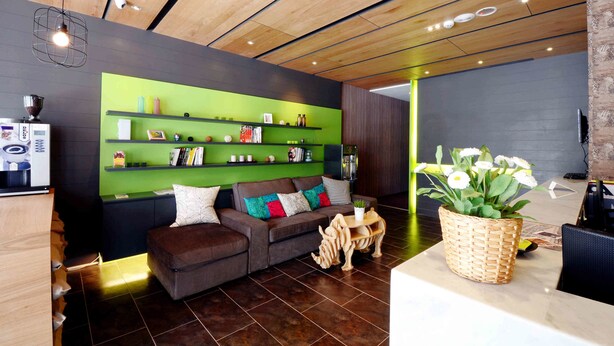Uma sala de estar moderna com um sofá, uma mesa de centro e uma prateleira fixada na parede com livros e objetos decorativos.