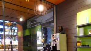 Interior moderno com teto de madeira, parede de vidro e máquina de café numa prateleira.