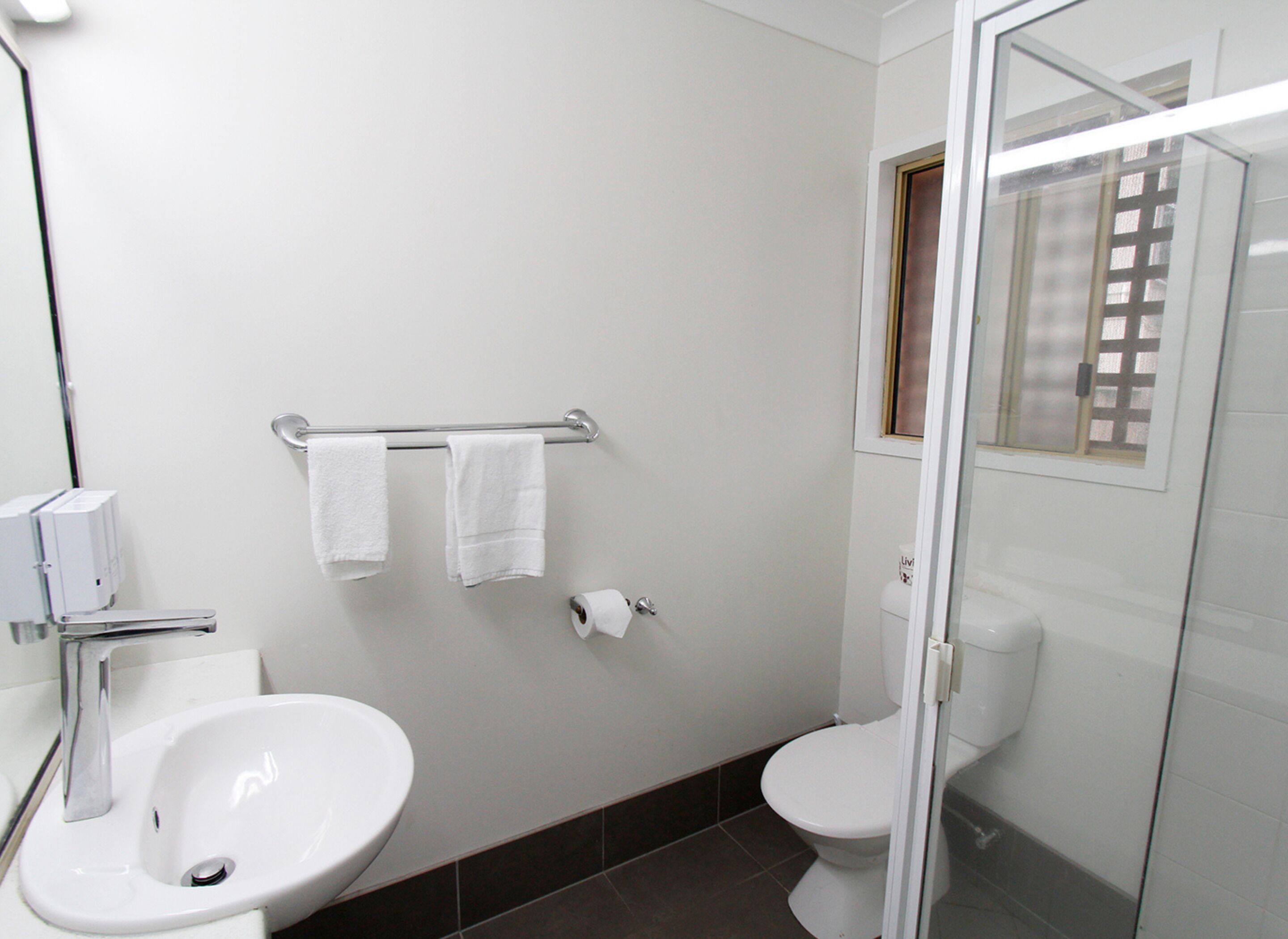 Uma casa de banho moderna com lavatório branco, sanita e cabine de duche em vidro.
