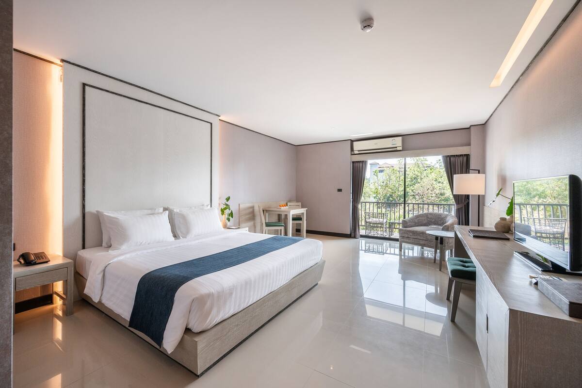 Quarto de hotel moderno com uma cama grande, uma escrivaninha, uma cadeira e uma televisão.