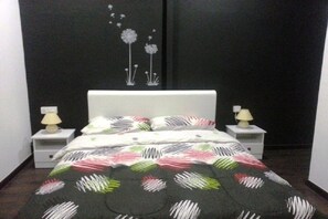 Quarto com uma cama, duas mesas de cabeceira e um adorno na parede.