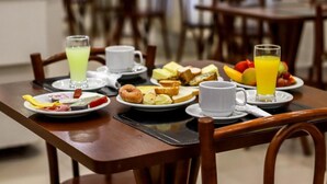 Mesa de madeira com pratos de comida, uma xícara de café e um copo de suco de laranja.