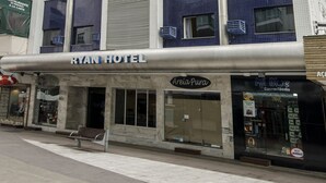 Um hotel com vários andares e design moderno, com uma placa chamativa “RYAN HOTEL” no nível térreo.