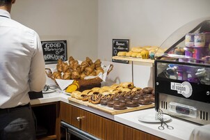 Um buffet de café da manhã com diversos pães e uma máquina de café.