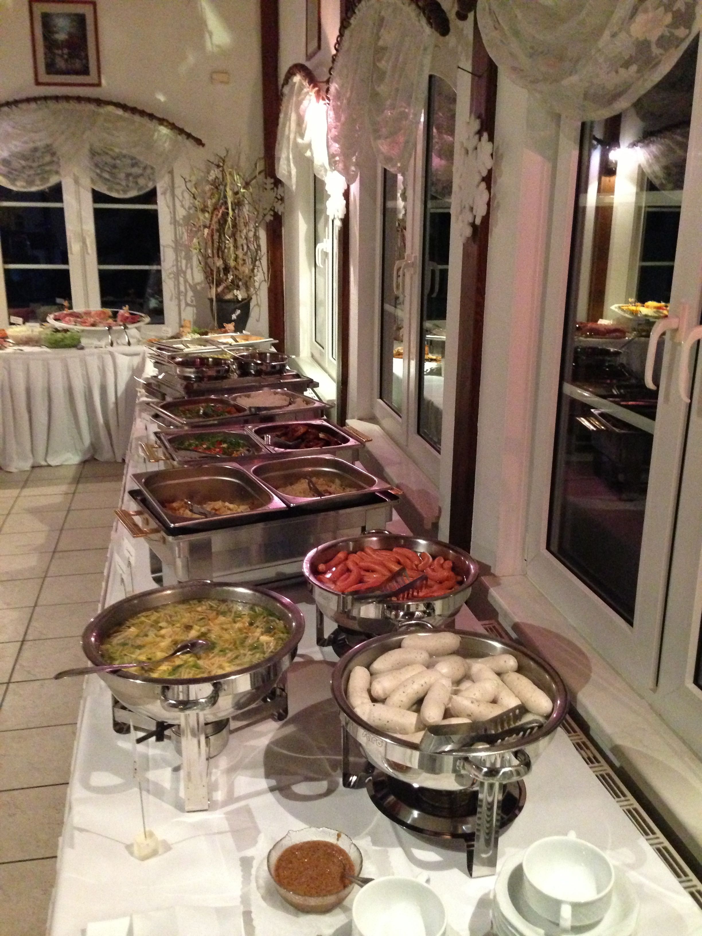 Buffet montado com diversos alimentos e área de refeições com vista para o céu noturno.