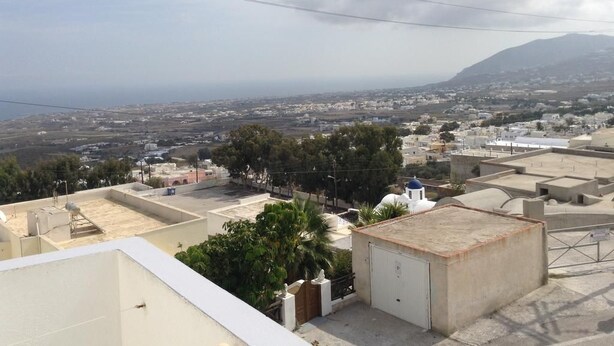 Área residencial com edifícios, alguns com telhados planos e outros inclinados, e uma vista distante da costa.