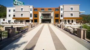 Um hotel com entrada central, área de estar externa e vista clara da paisagem circundante.