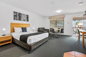Quarto de hotel com uma cama, uma escrivaninha e uma cadeira.