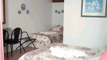 Quarto com duas camas, uma cadeira e decorações nas paredes.