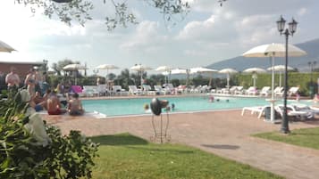 Uma área de piscina com espreguiçadeiras e guarda-sóis.