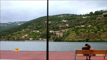 Um banco com vista para um corpo d'água e uma encosta ao fundo.
