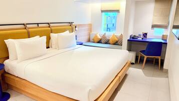 Quarto de hotel com cama, escrivaninha e janela com vista.