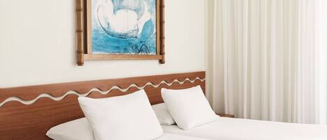 Quarto de hotel com cabeceira de madeira, duas almofadas brancas, um quadro abstrato grande e uma janela com cortinas brancas.