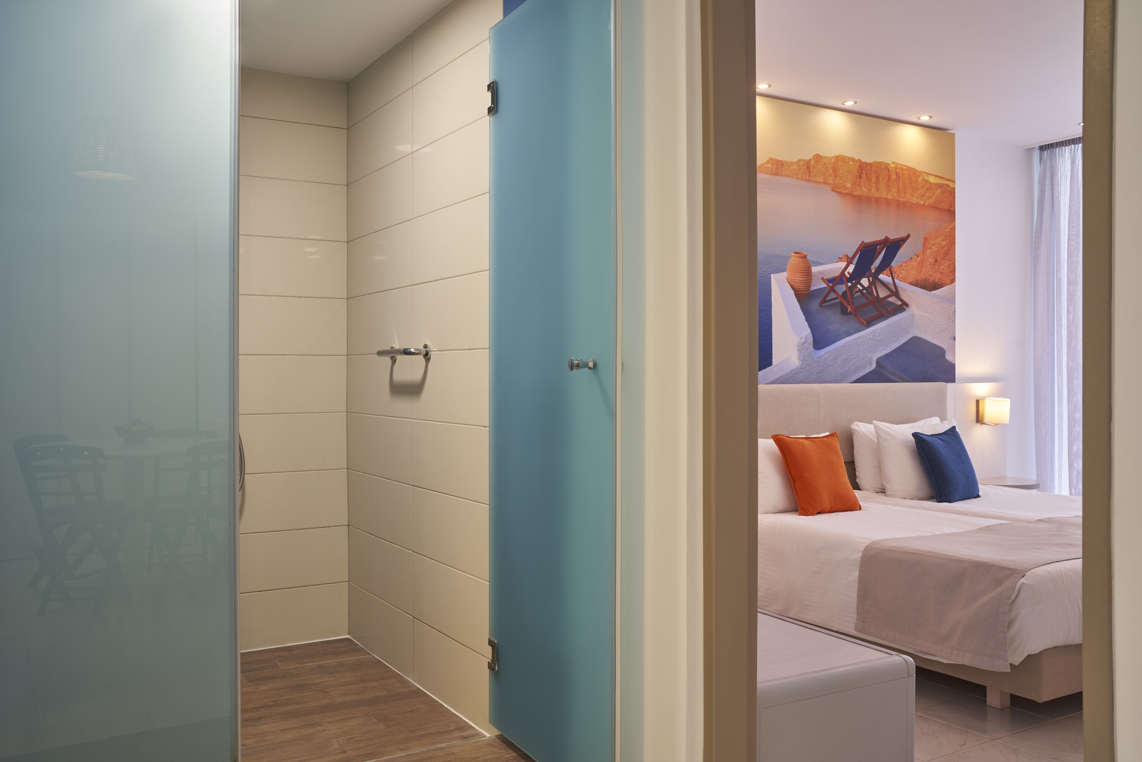 Quarto de hotel com uma cama grande, um pequeno espaço para sentar e um mural com uma cena de praia.
