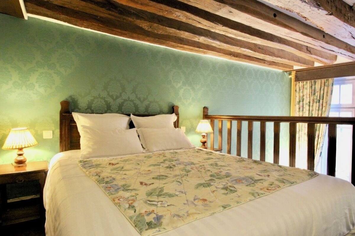 Quarto com colcha florida, cabeceira de madeira e mesa de cabeceira com abajur.