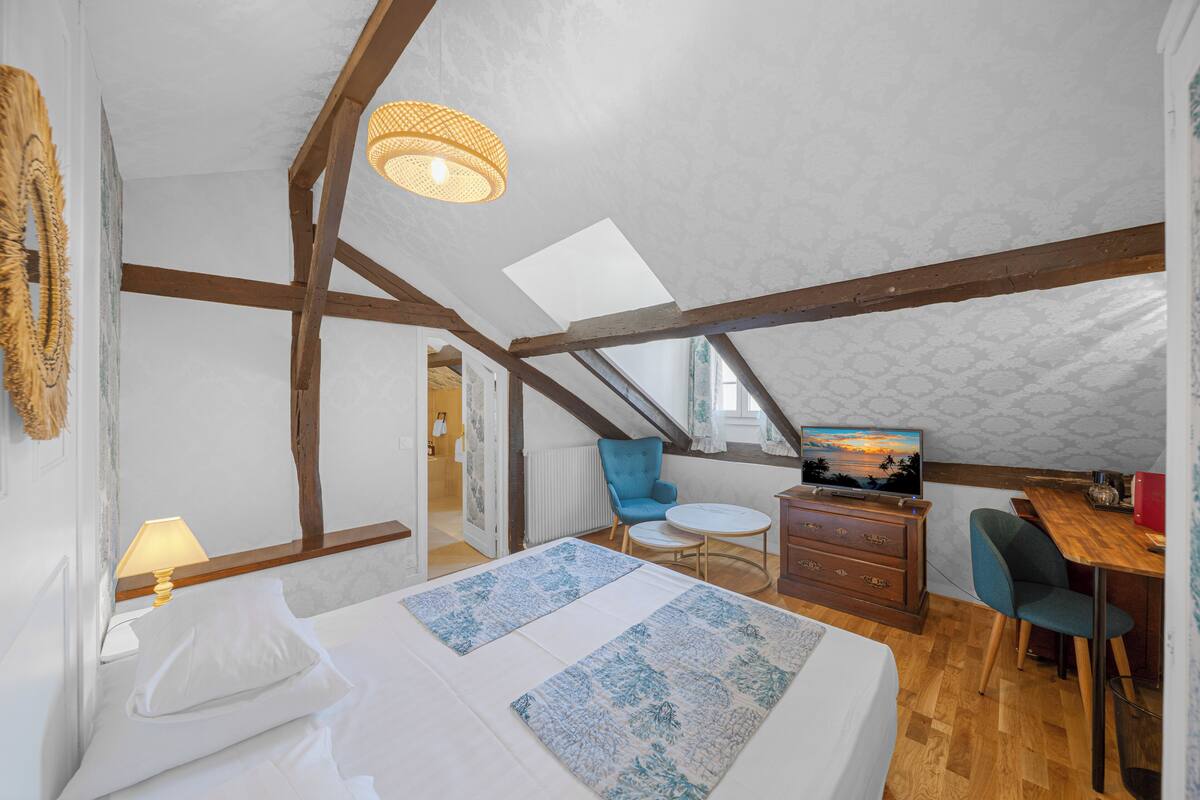 Quarto com cama, escrivaninha, cadeira, luminária, televisão e janela.