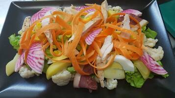 Salada com diversos vegetais e frango num prato preto.
