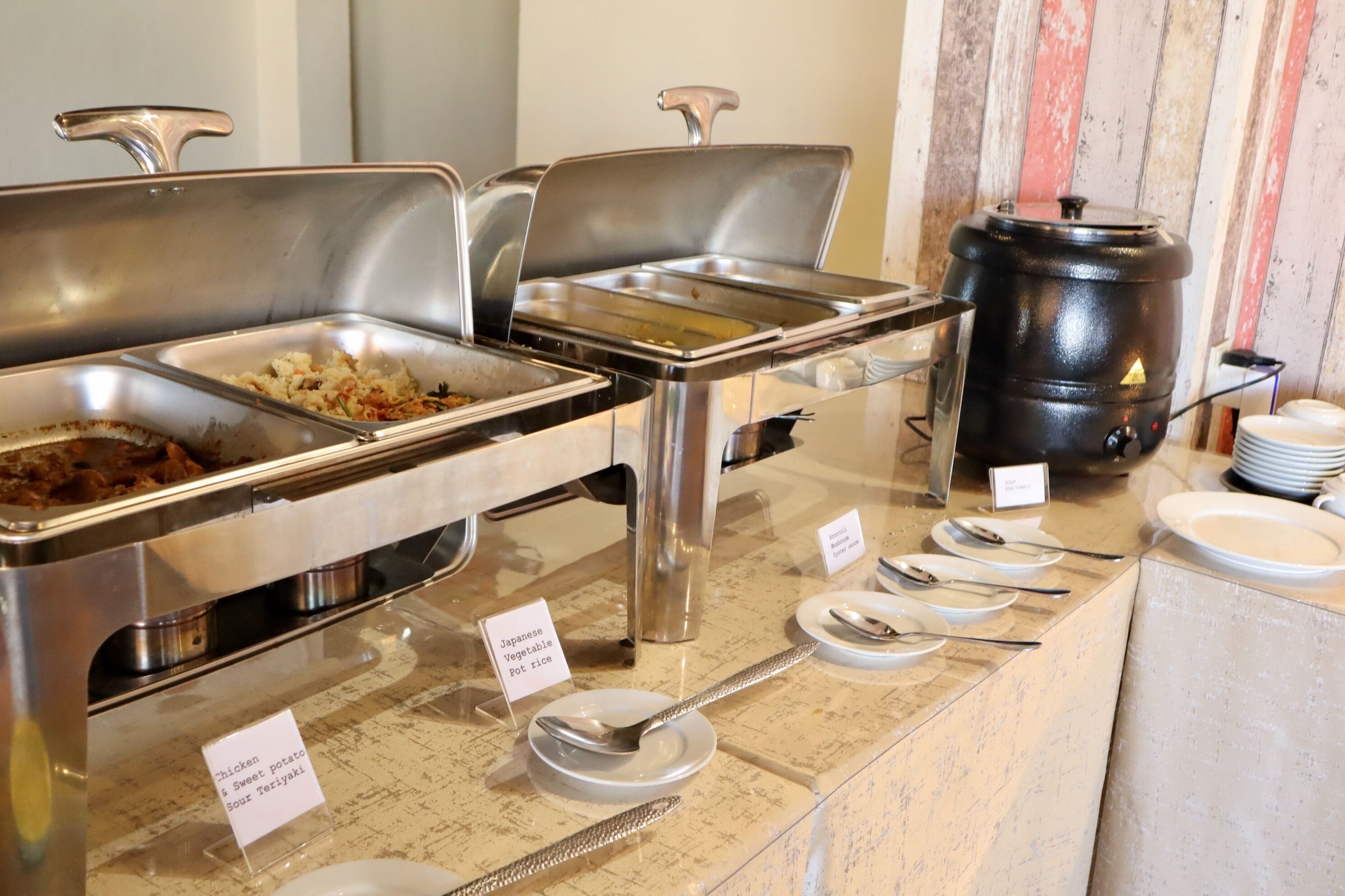 Disposição de buffet com pratos identificados, incluindo Arroz com Legumes e Vegetais Japoneses, Frango e Soufflé de Batata Doce.