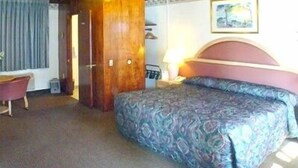 Quarto de hotel com uma cama, uma mesa, uma cadeira e uma porta.