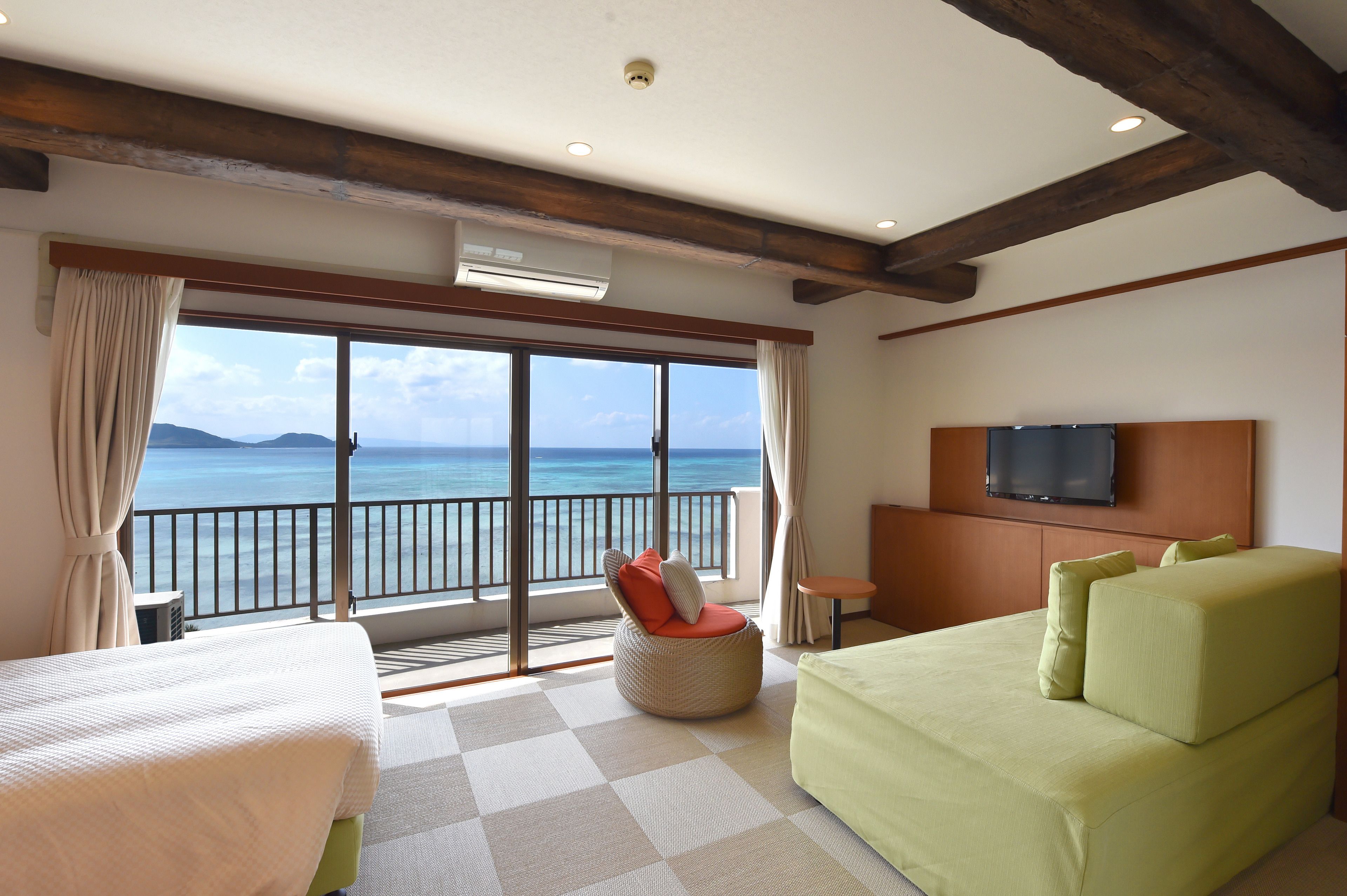 Quarto de hotel com varanda, cama, sofá e televisão.