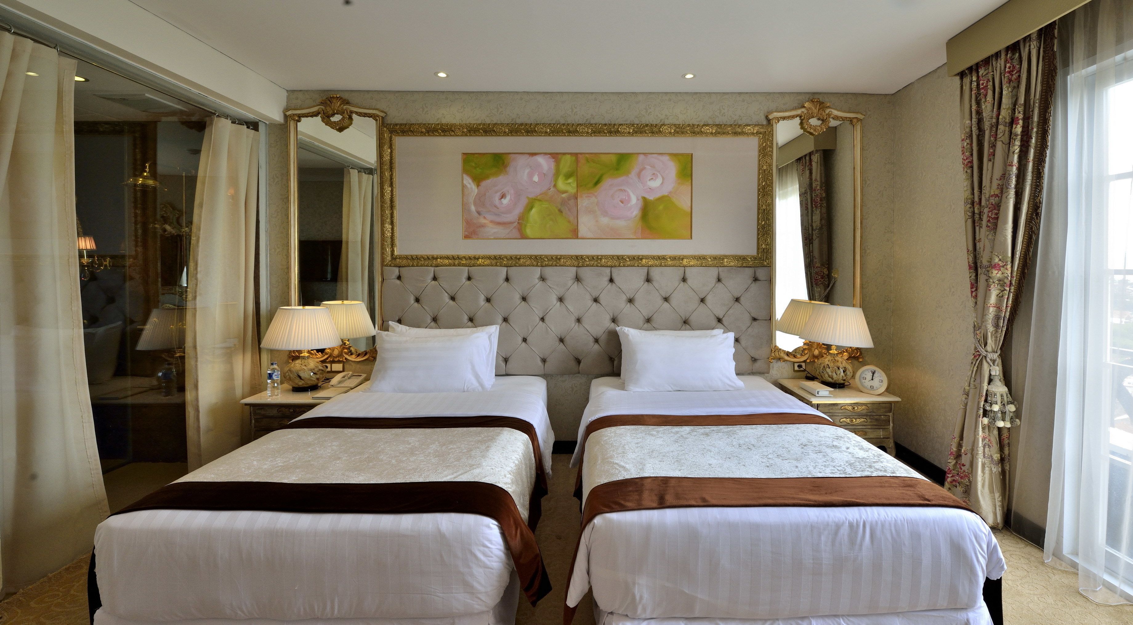 Quarto de hotel com duas camas, um espelho grande e um quadro na parede.