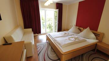 Quarto de hotel com cama, sofá, escrivaninha e janela com cortinas.
