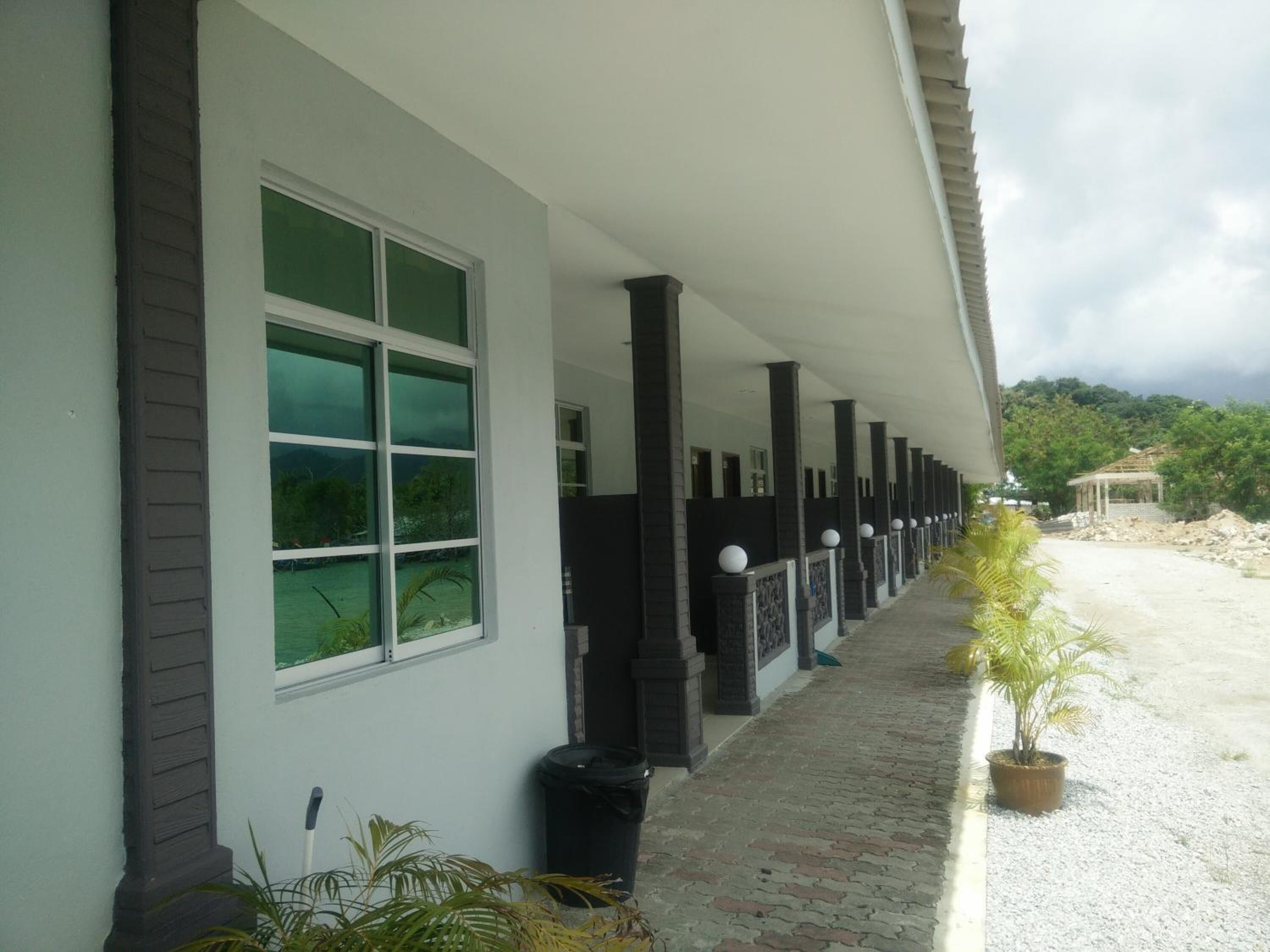 Uma área externa coberta com colunas e um caminho que leva à entrada de um edifício.