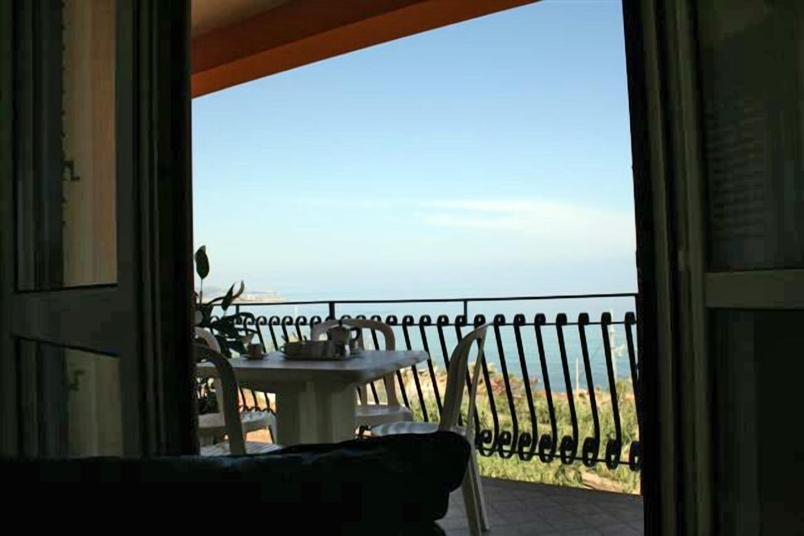 Varanda com mesa e cadeiras, com vista para a paisagem costeira.