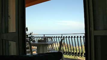 Varanda com mesa e cadeiras, com vista para a paisagem costeira.