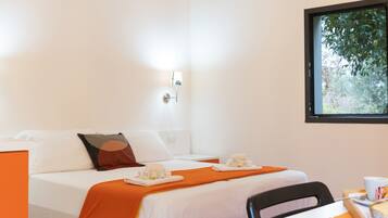 Quarto de hotel com cama, mesa e janela vista para árvores.