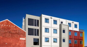 Um edifício moderno com fachada de tijolos e uma seção superior branca com várias janelas.