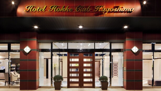 A entrada do Hotel Hokke Club-Kagoshima, com um design moderno, apresenta uma placa de destaque e entrada por porta de vidro.