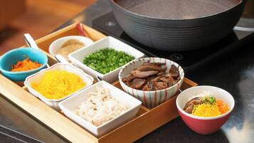 Uma bandeja com diversos alimentos, incluindo arroz, legumes desfiados e carne, juntamente com uma panela de sopa.