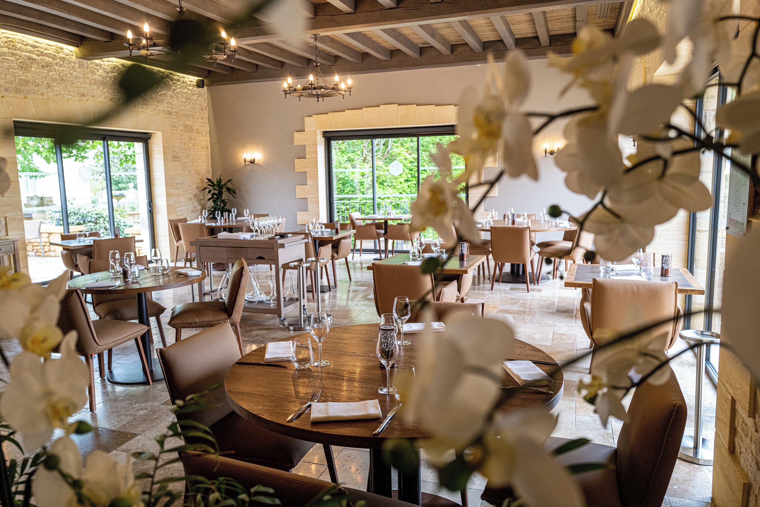 Um restaurante com mesas redondas, cadeiras e um lustre.