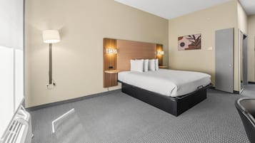 Quarto de hotel com cama, mesa de cabeceira, luminária, obra de arte e guarda-roupa.