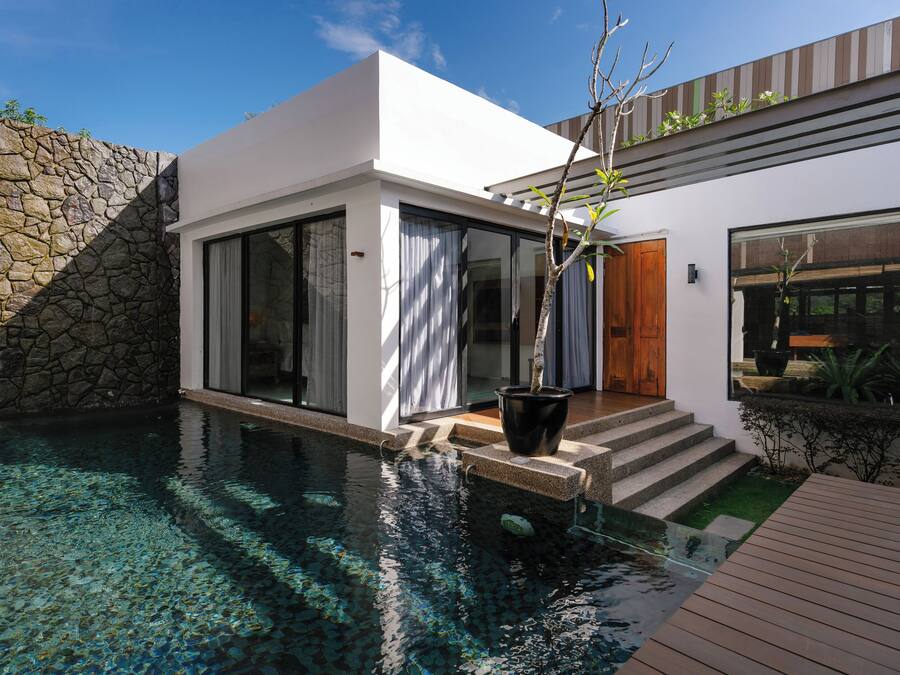 Uma casa moderna com piscina, muro de pedra e deck de madeira.