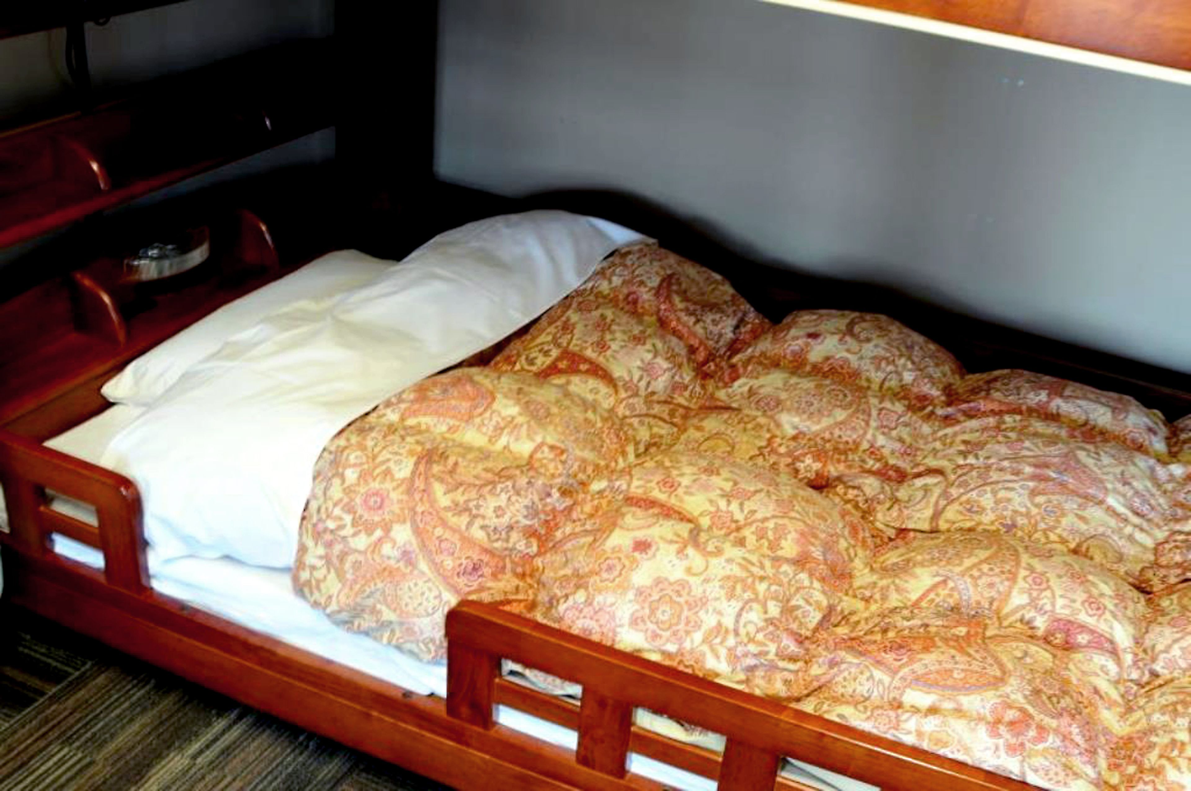 Uma cama com um cobertor estampado e um travesseiro branco.