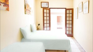 Quarto com duas camas, mesa de cabeceira, luminária e obras de arte nas paredes.