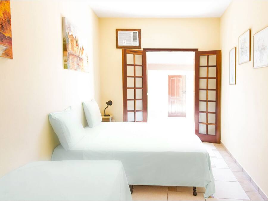 Quarto com duas camas, mesa de cabeceira, luminária e obras de arte nas paredes.