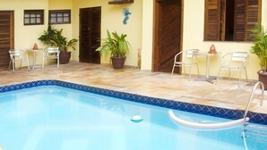 Piscina interior em vários níveis, com teto de vidro, guarda-corpos de madeira e plantas em vasos.