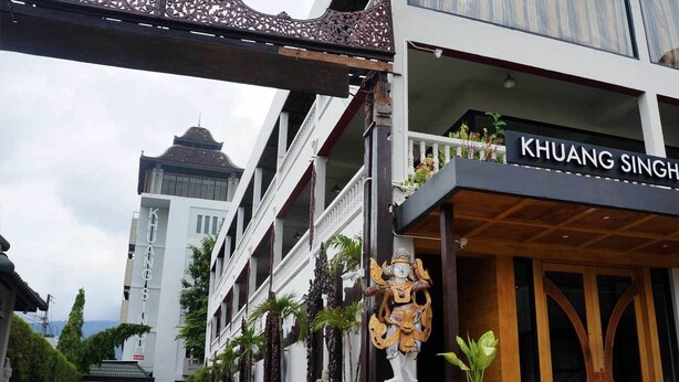 Entrada de hotel com um portão tradicional e uma placa com a inscrição 'KHUANG SINGH'.