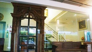 Uma área de recepção com um balcão de madeira, um banco e uma porta de vidro que dá para uma escadaria.