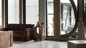 Um interior moderno com um sofá de madeira, uma mesa pequena e uma janela grande com vista para a rua.