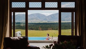 Quarto com uma grande janela com vista para uma paisagem montanhosa.