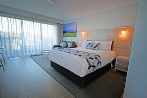 Um quarto moderno com uma cama grande, uma cadeira, uma mesinha e um quadro na parede.