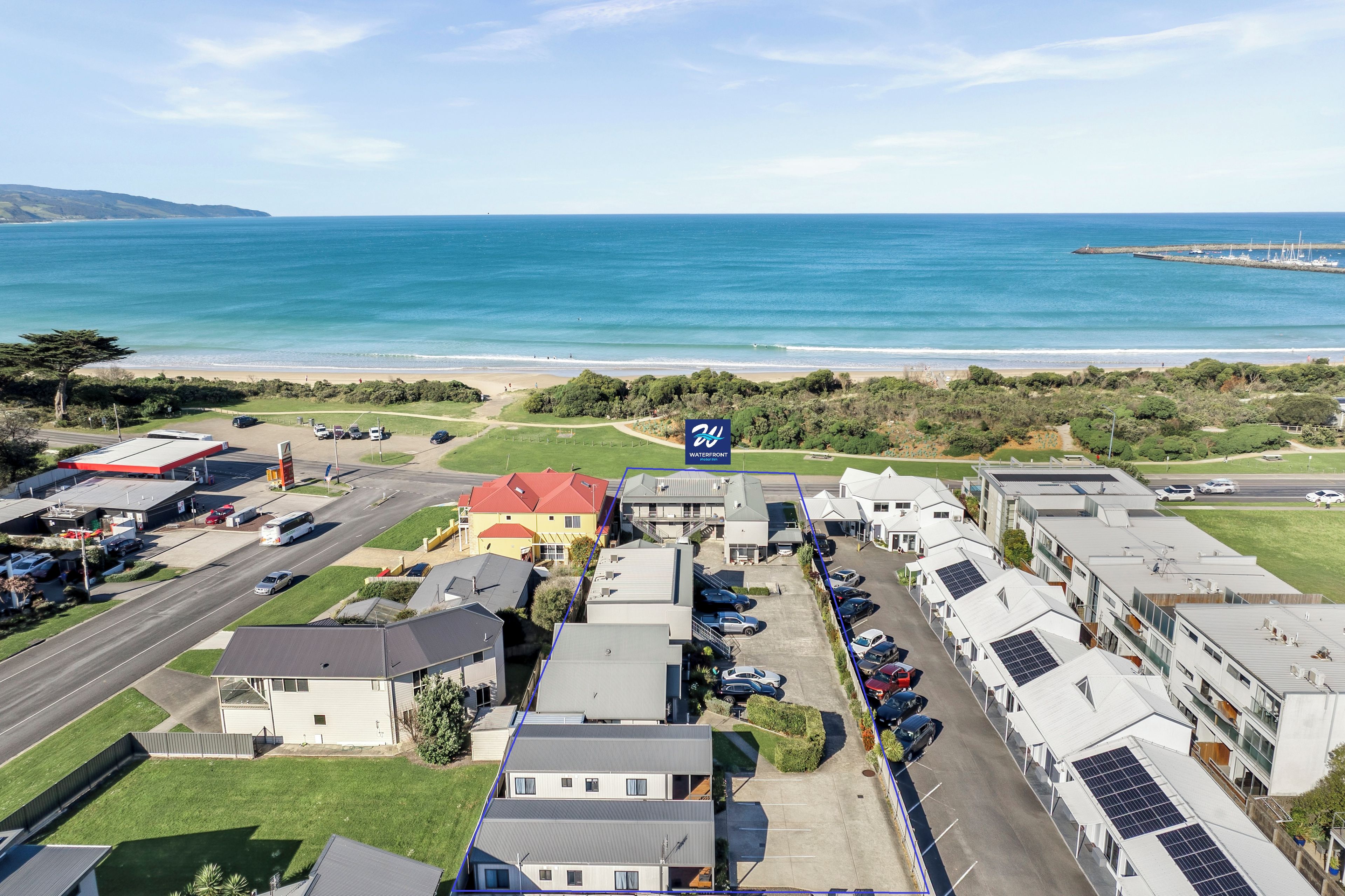 Uma área residencial à beira-mar, com casas, uma estrada e uma praia.