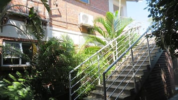 Escada com corrimão de metal que leva a um edifício de tijolos com unidade de ar condicionado.