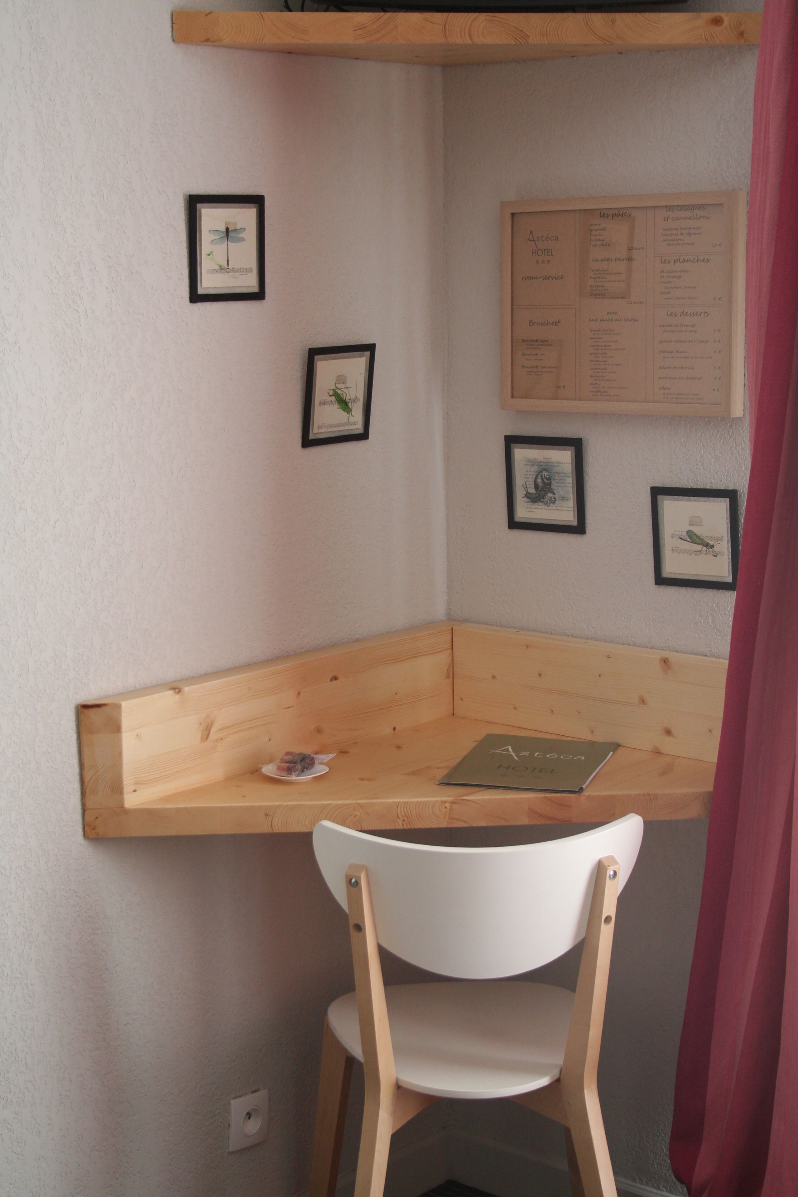 Uma mesa de canto com cadeira, quadros nas paredes e um quadro de menu.
