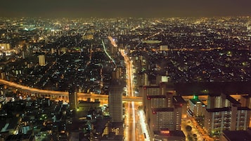 Paisagem urbana noturna com uma rodovia em destaque e edifícios urbanos densos.